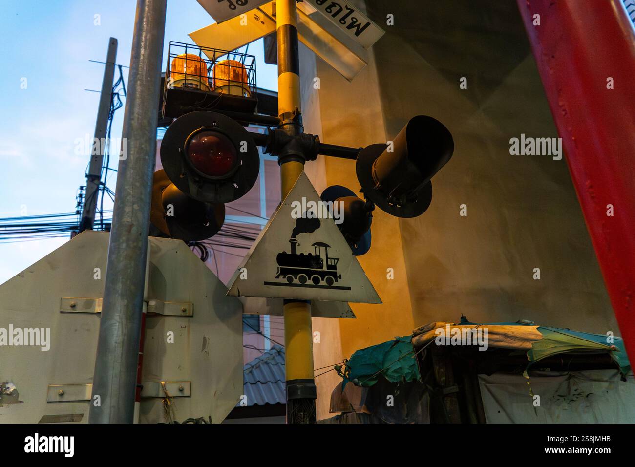 Train crossing signal at dusk with warning lights and a traditional ...
