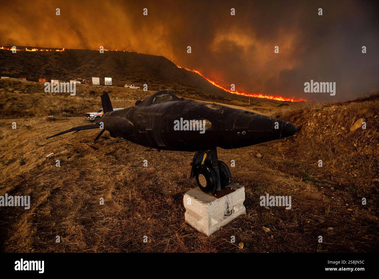 A charred replica of an aircraft sits in a paintball course as flames ...