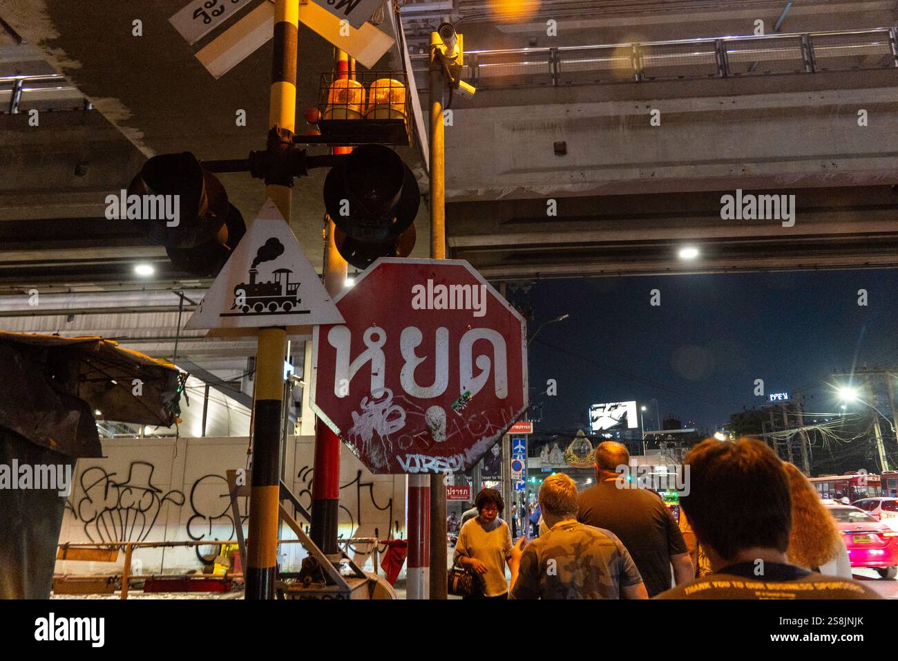 Stop sign and railway crossing at night in a busy urban area with ...