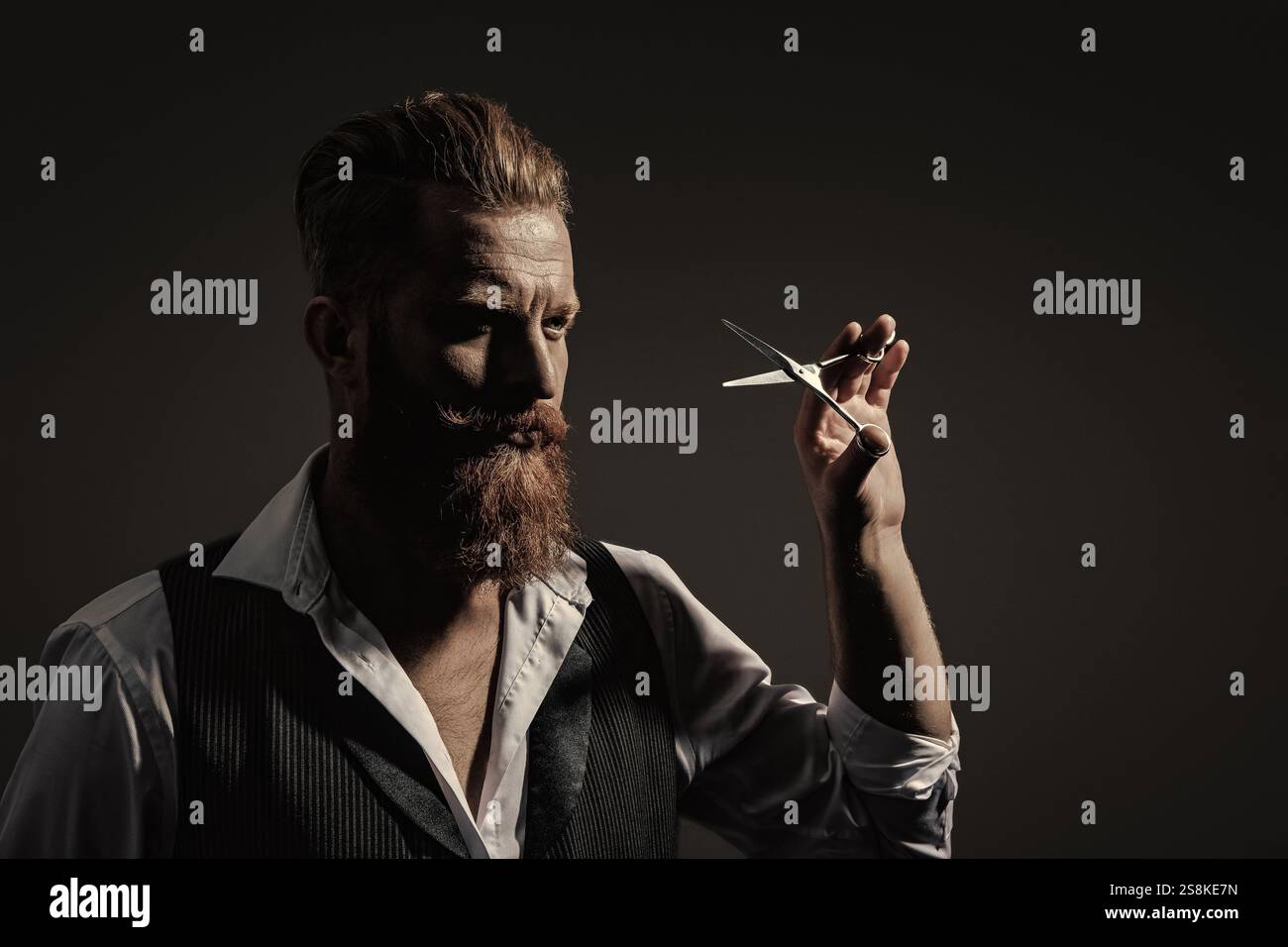 Handsome barber using scissors while cutting hair. Modern barbershop ...