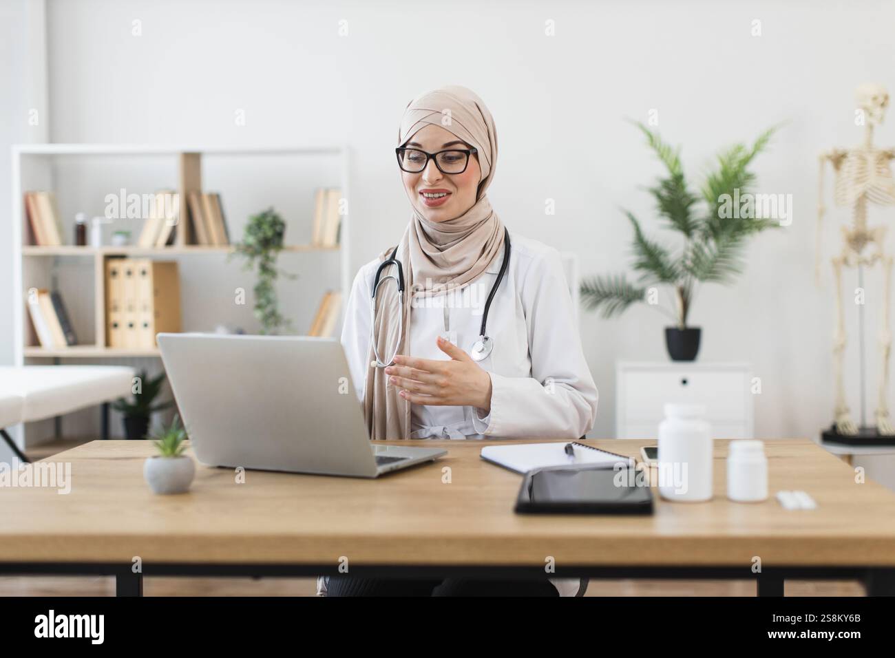 Young Muslim female doctor having online consultation using laptop ...