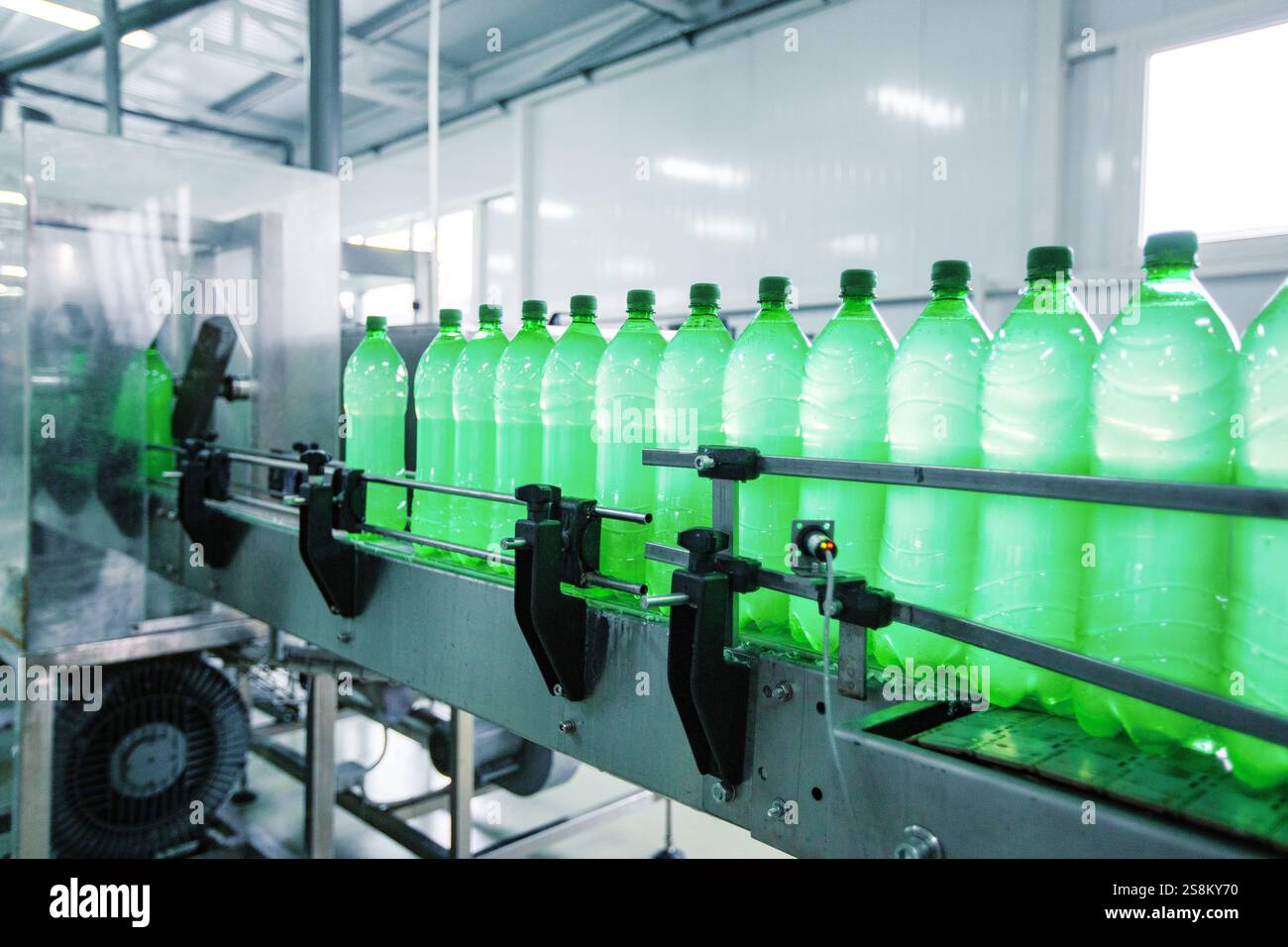 Bottles of green beverage on the assembly line in a production facility ...
