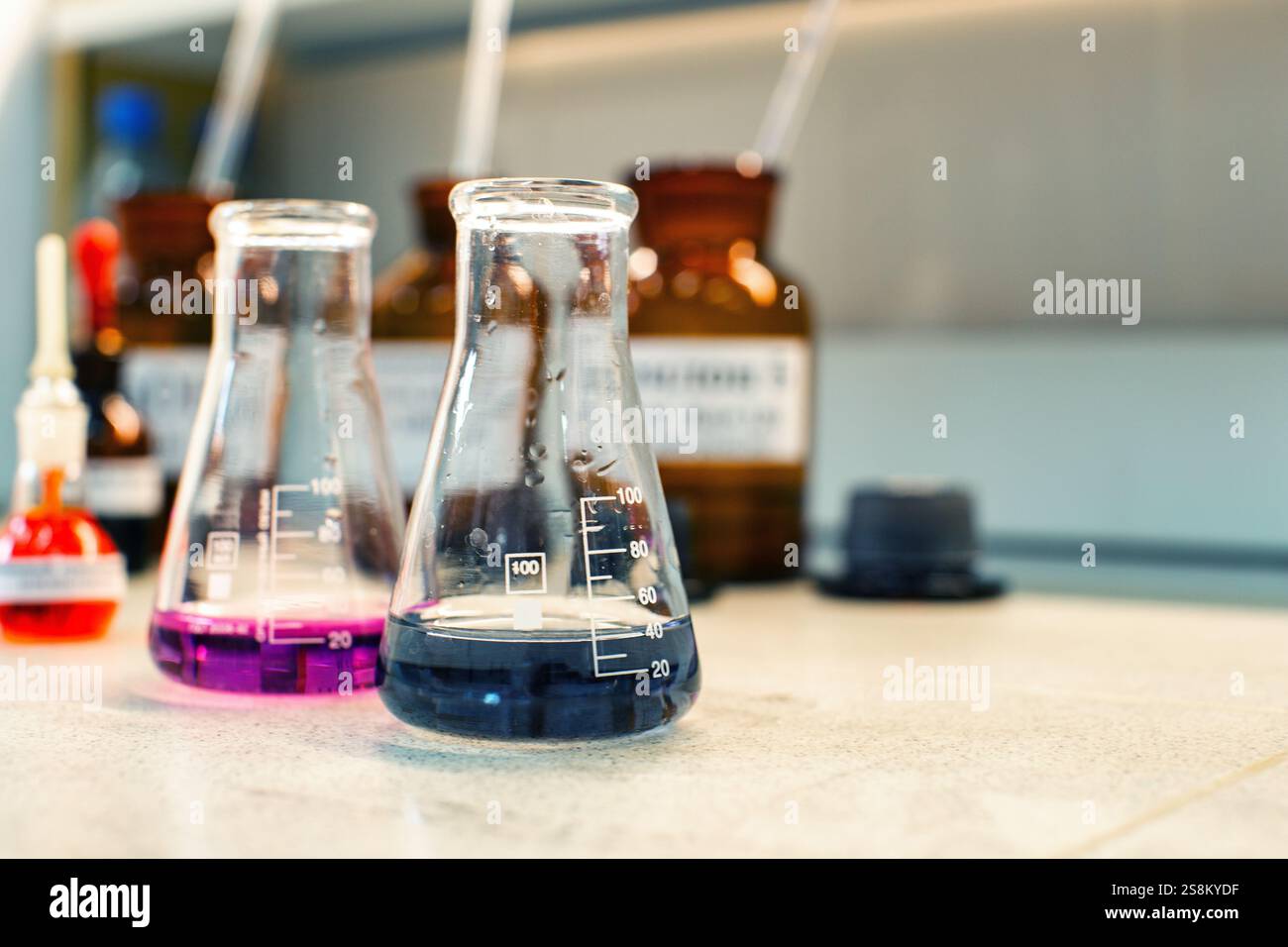 Glass containers with colored liquids on laboratory countertop during ...