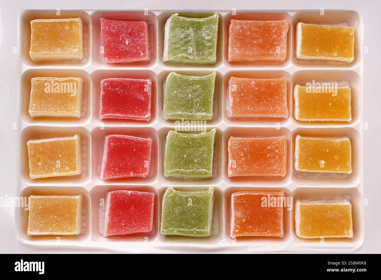Colorful jelly squares arranged in a neat grid on a white tray ...
