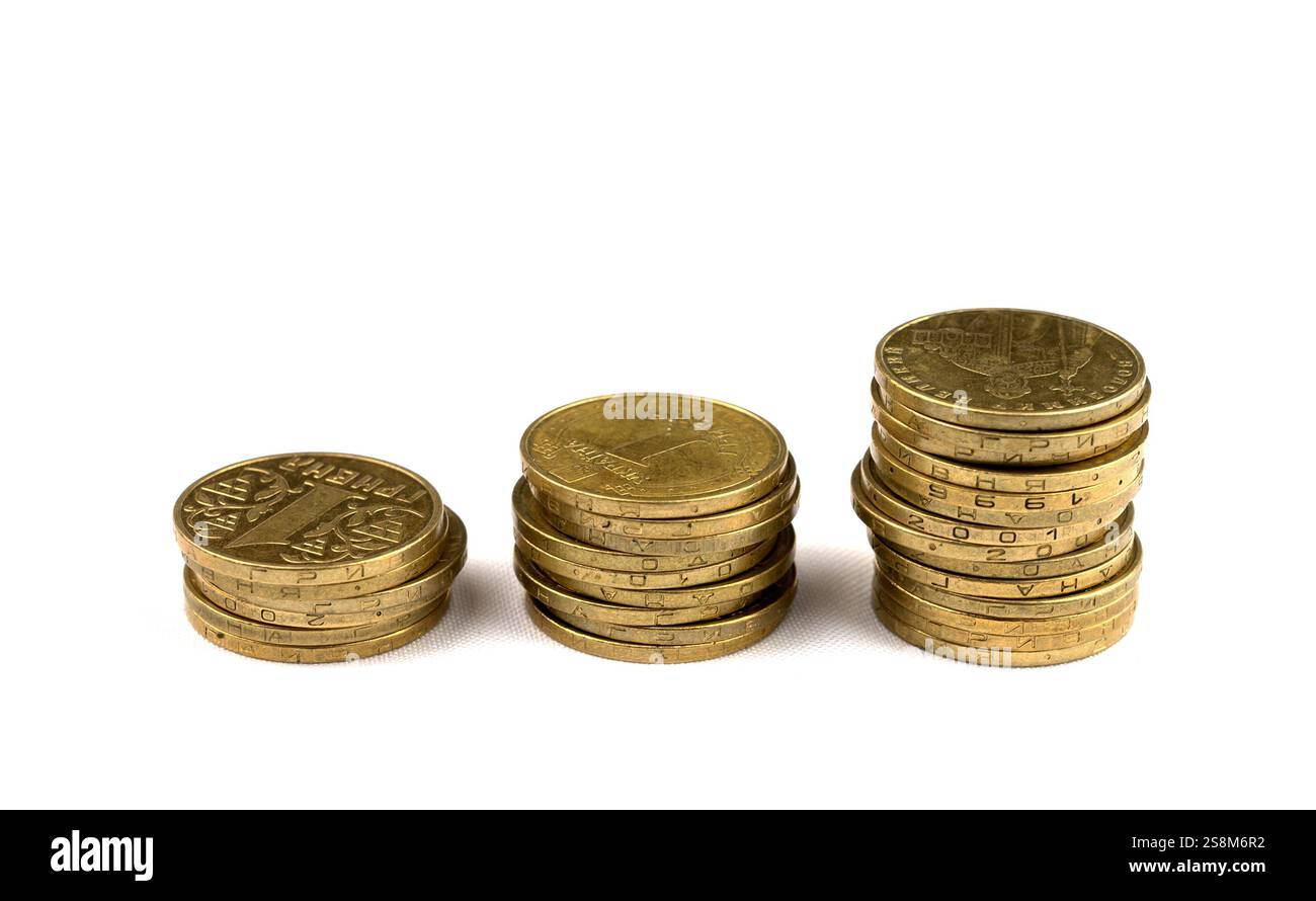 Various stacks of coins are arranged on a clean, white surface ...