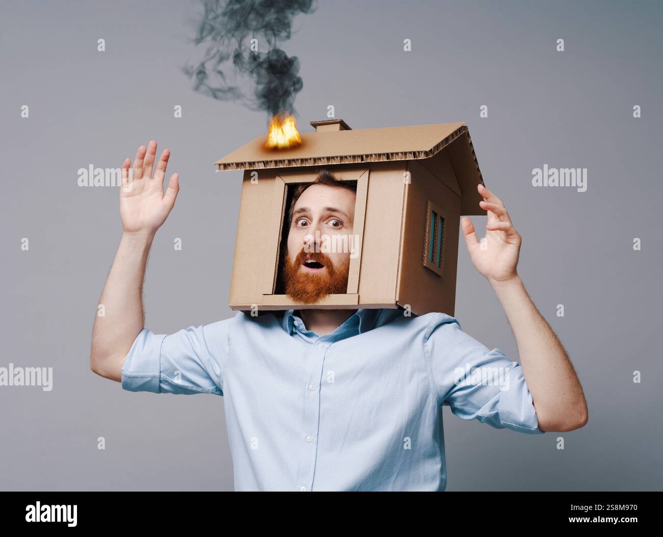Shocked screaming homeowner with his head inside a burning cardboard ...