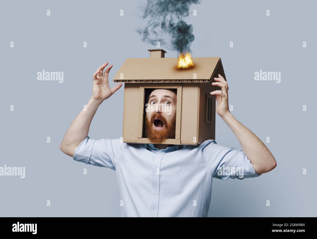 Shocked screaming homeowner with his head inside a burning cardboard ...