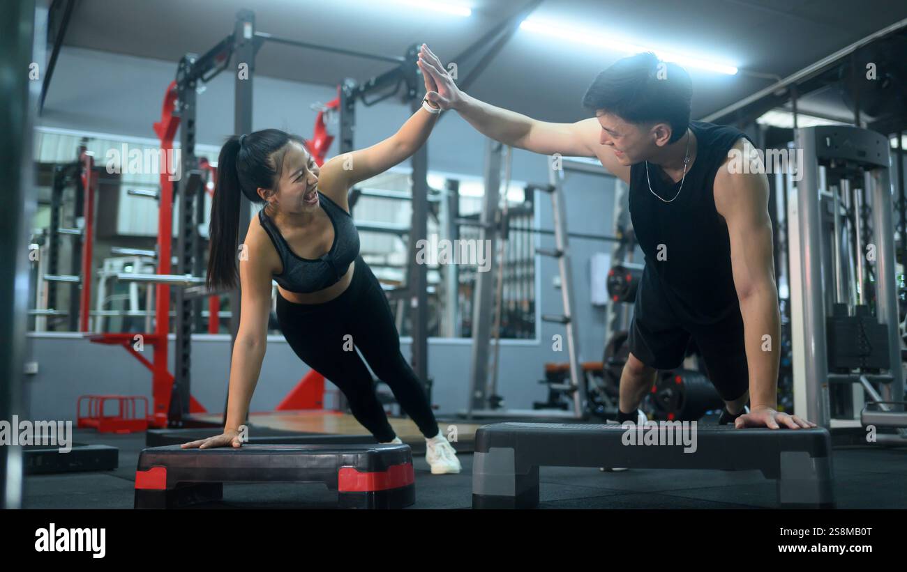 Active couple giving high five each other while doing push up on step ...