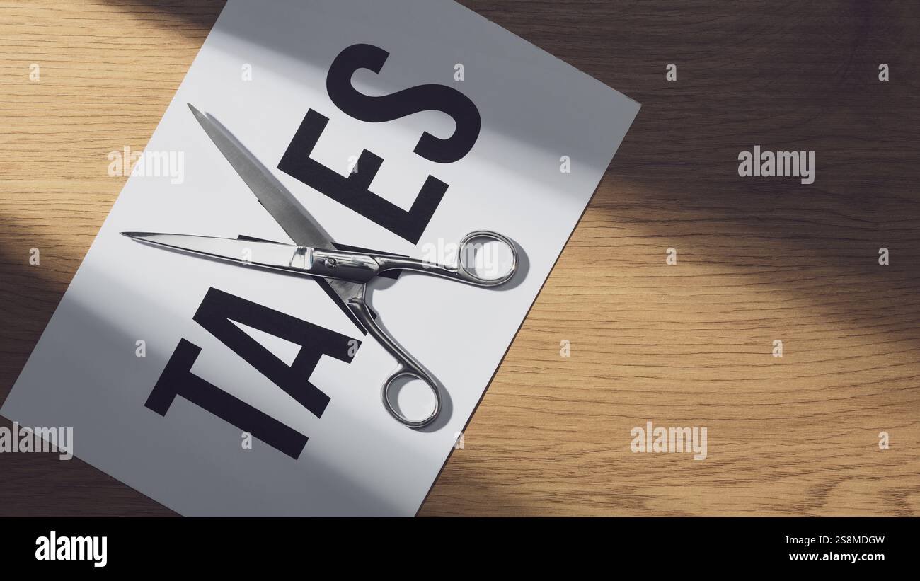 TAXES text on a sheet and scissors: tax cut and tax reduction concept ...