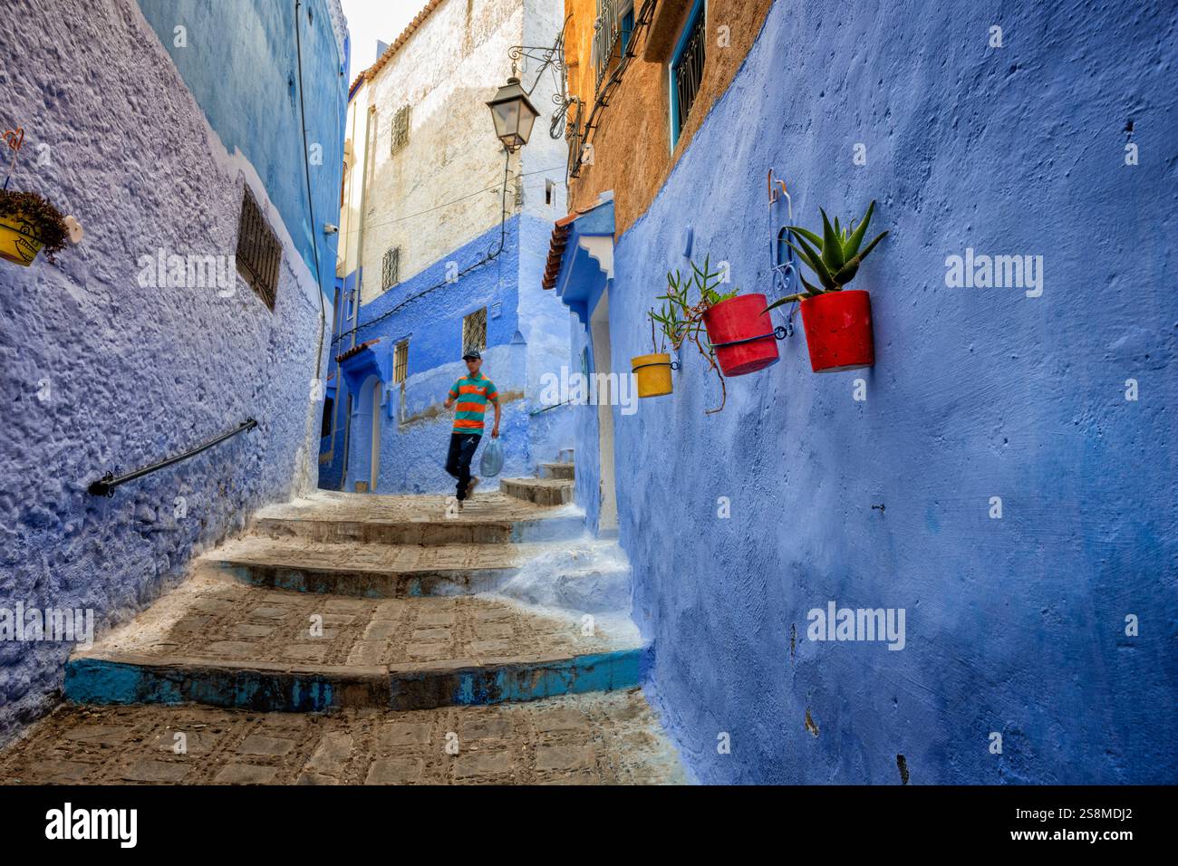 Chefchaouen, Morocco. Red and yellow pots on a blue wall. Alley inside ...