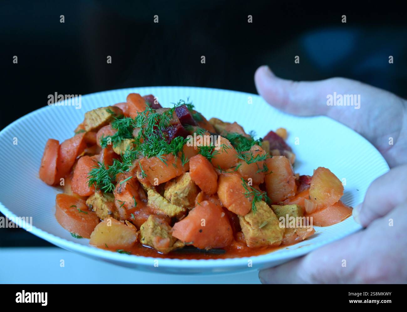 Beef stew with vegetables in chef hands on dark background Stock Photo ...