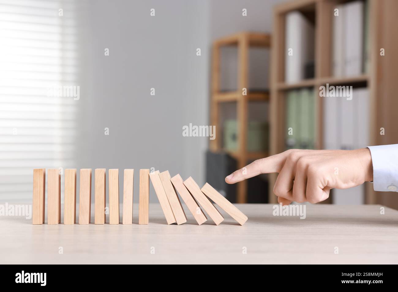 Domino effect. Man pushing wooden blocks at table, closeup Stock Photo ...