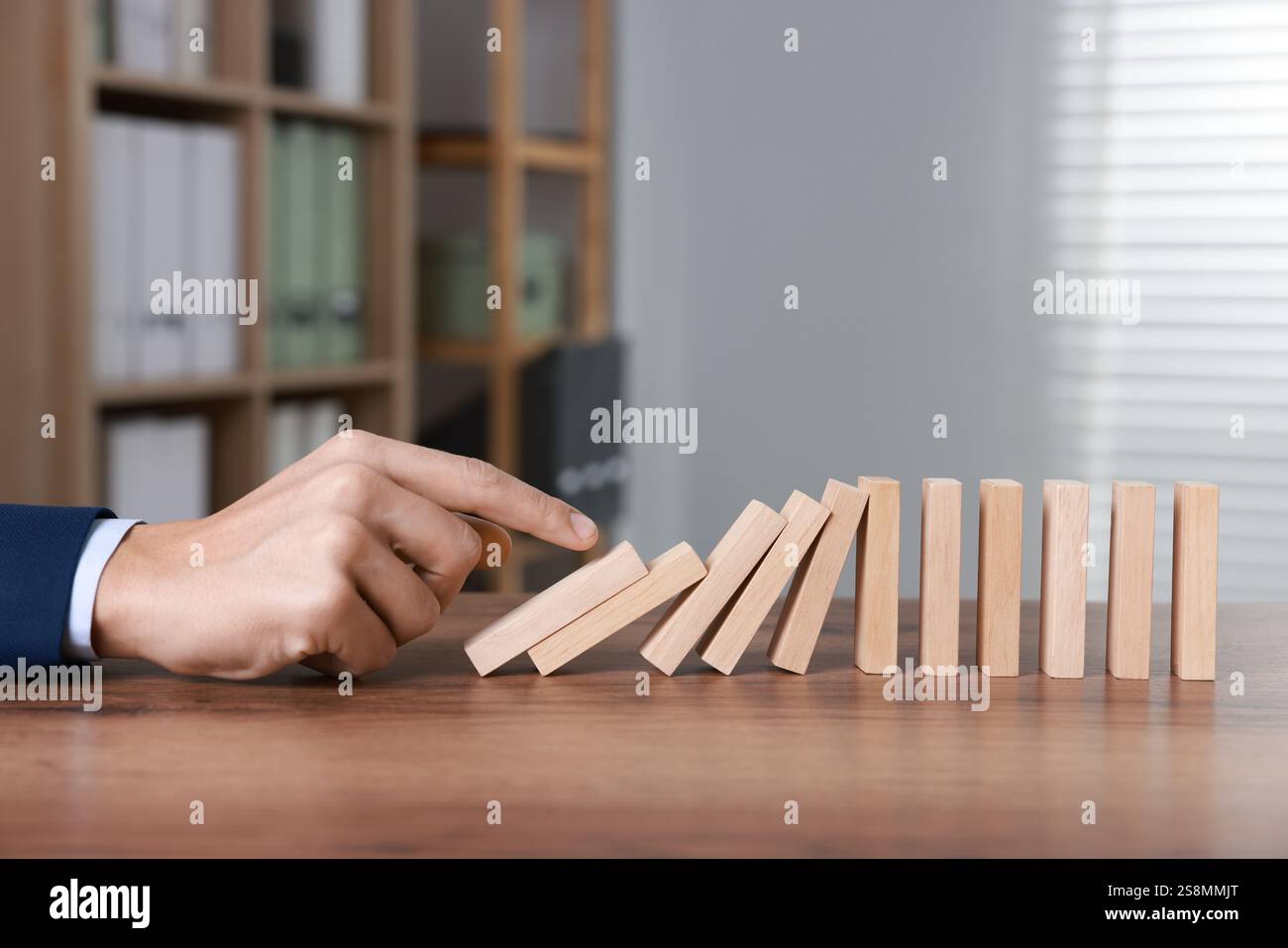 Domino effect. Man pushing wooden blocks at table, closeup Stock Photo ...
