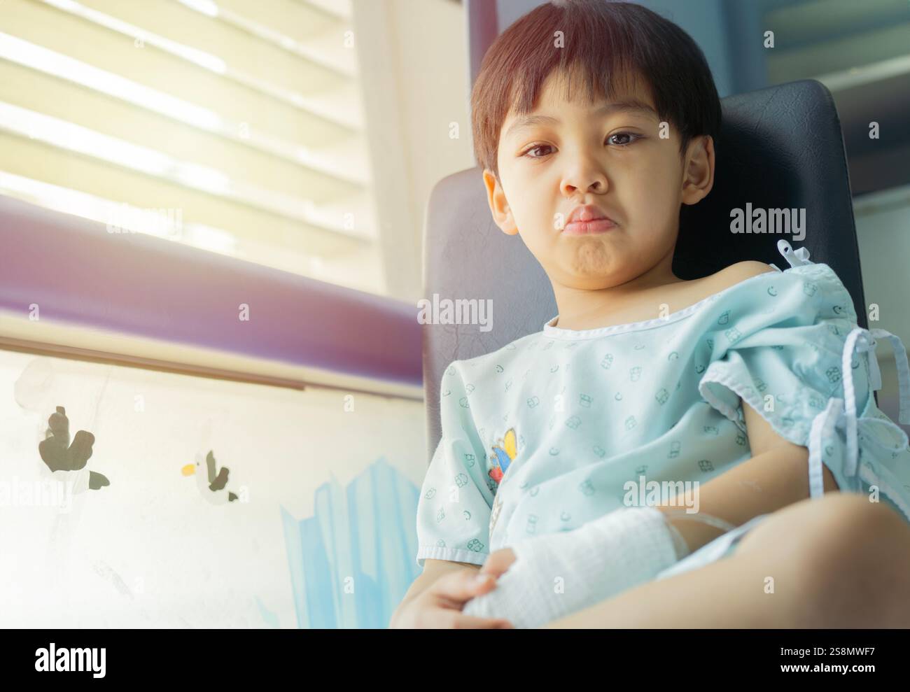 Portrait of sick little Asian boy feeling worry with saline solution ...