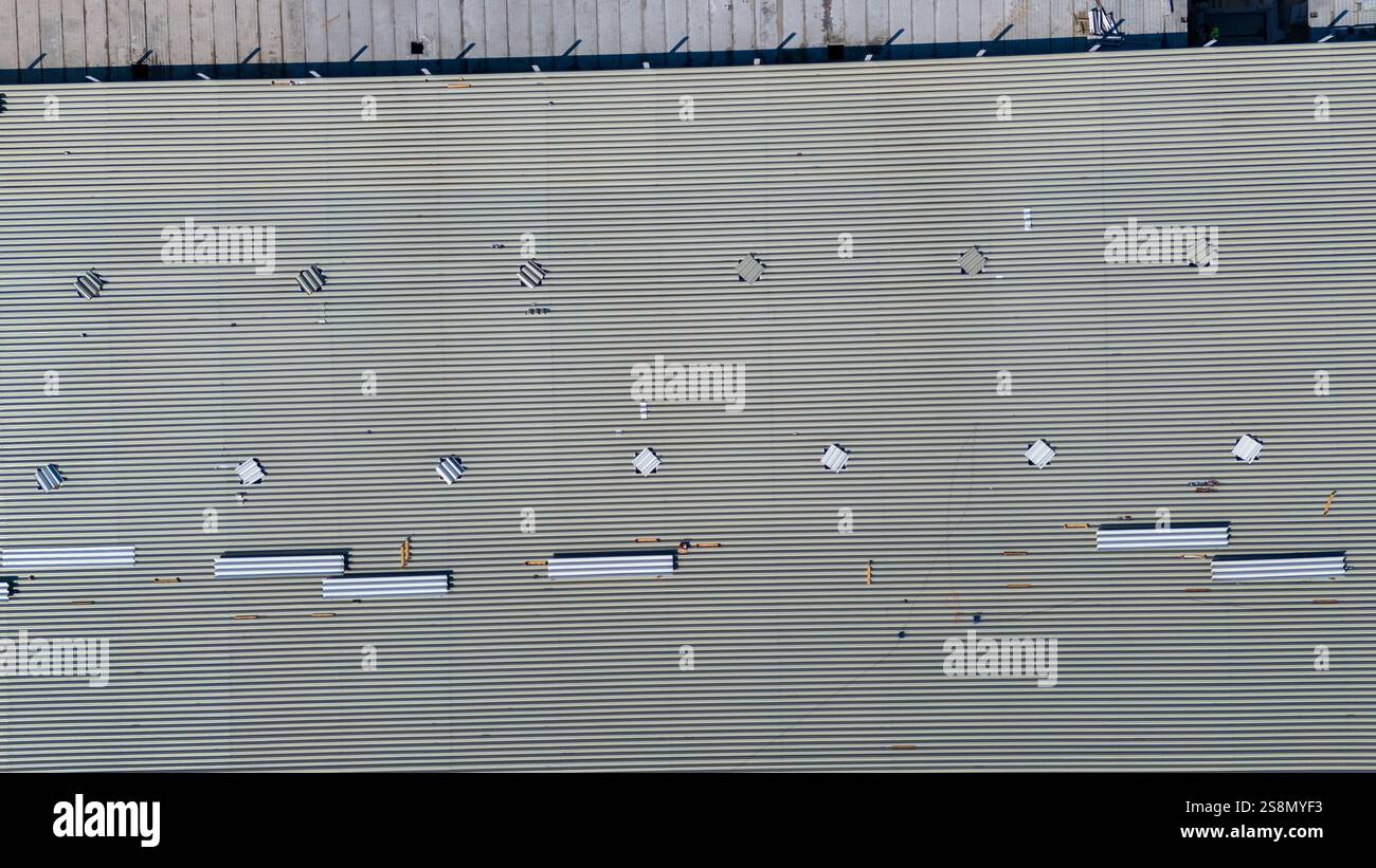 Aerial view of a large industrial metal roof with visible damage and ...