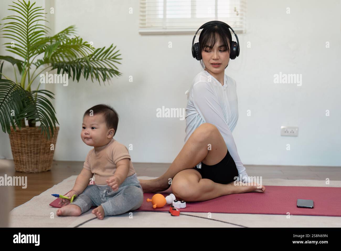 Multitasking mother listening to music while exercising, keeping an eye ...