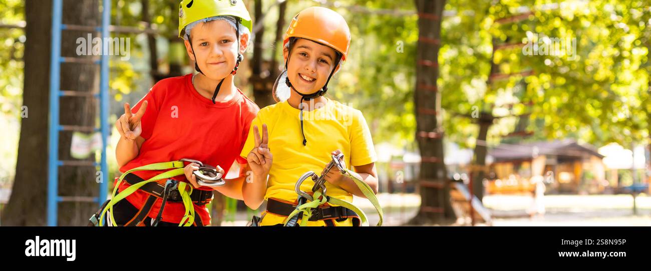 Small children climb a rope bridge in a rope park. Children are having ...