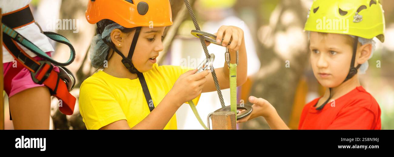 Small children climb a rope bridge in a rope park. Children are having ...