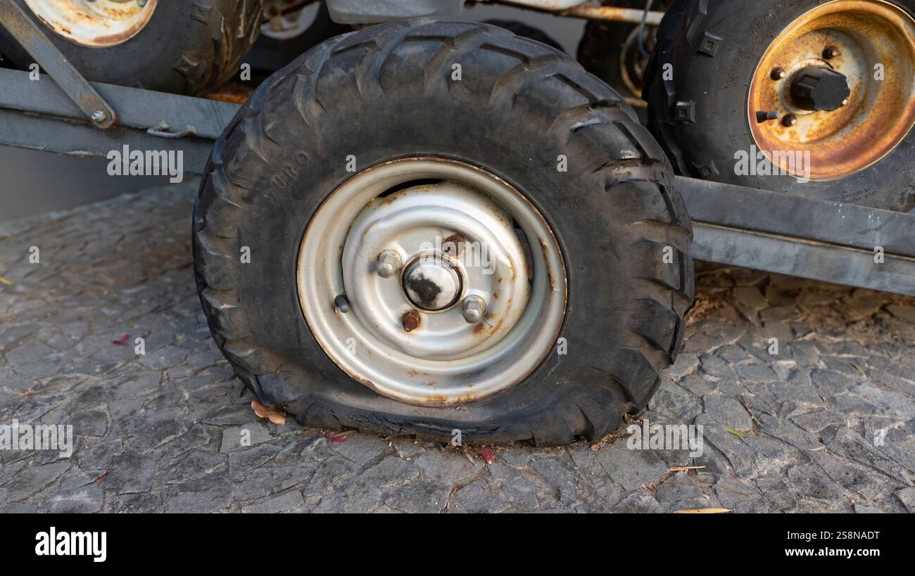 A close-up of a flat off-road tire on a trailer, showing worn-out ...