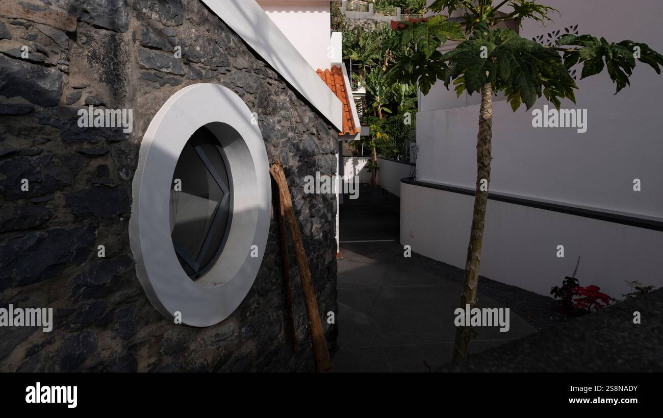 A modern house with a distinctive circular window set in a rustic stone ...