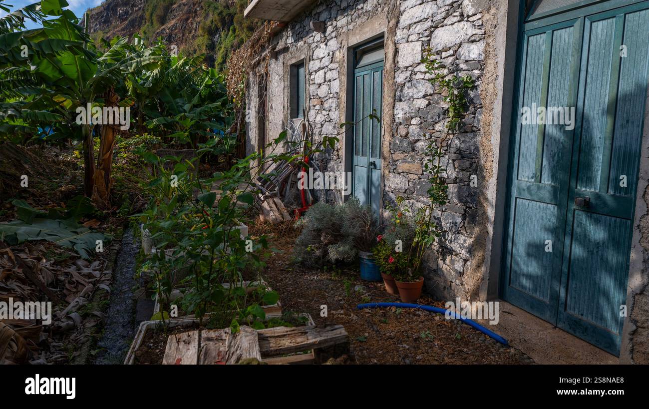 A rustic stone house with weathered blue wooden doors, surrounded by ...