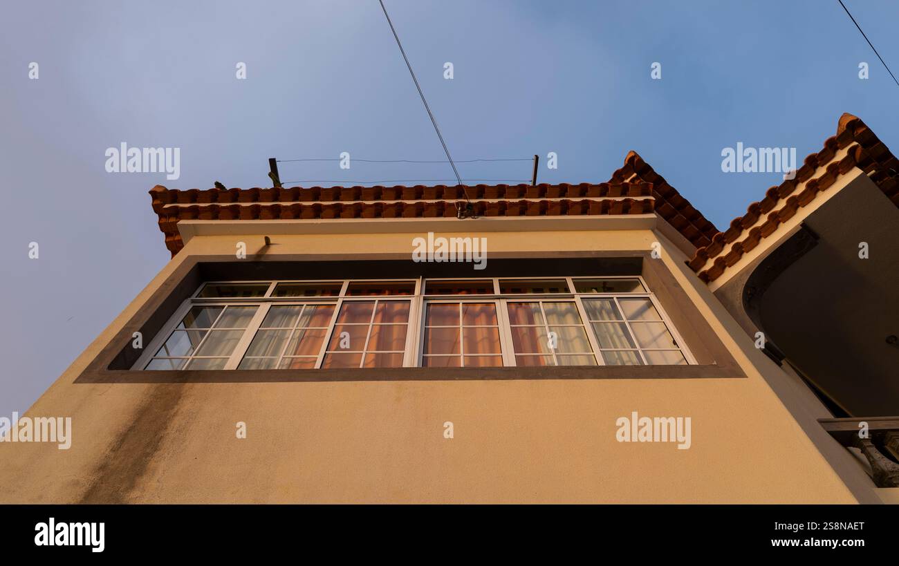 A low-angle view of a Mediterranean-style house with large windows and ...