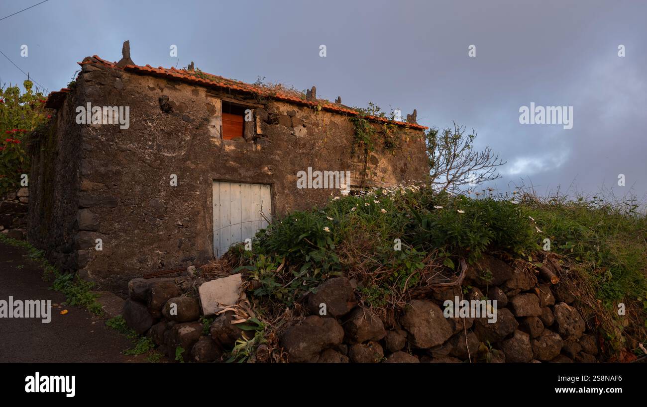 An old rural stone house with a red-tiled roof, showing signs of age ...