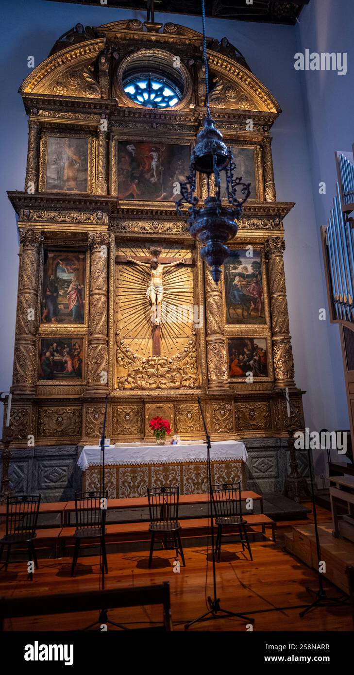An ornate golden church altar featuring a crucifix in the center, surrounded by religious ...