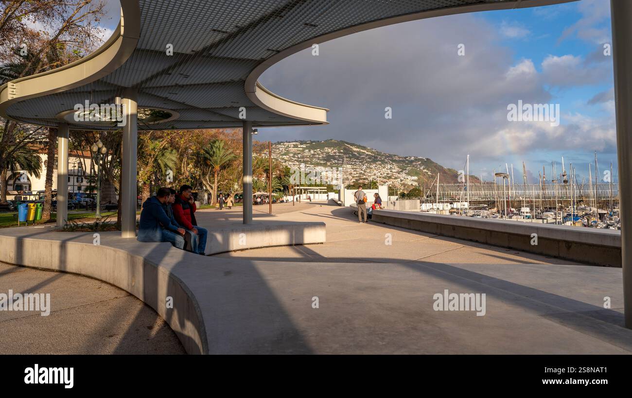 A modern outdoor pavilion with curved seating overlooking a marina ...