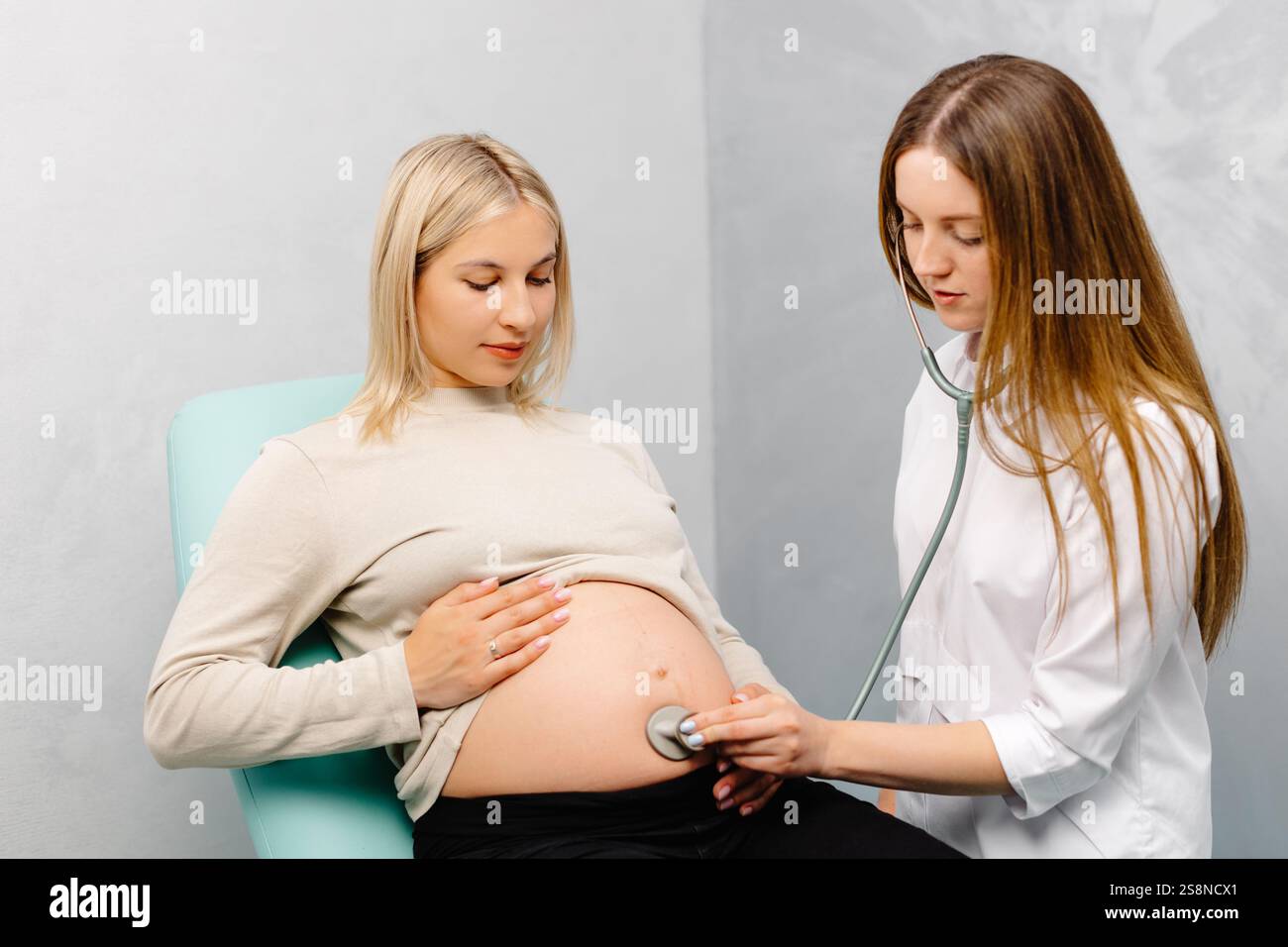 Female doctor using stethoscope examining pregnant woman in clinic ...