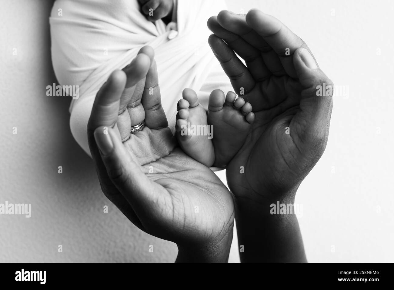 The palms of the father, the mother are holding the foot of the newborn ...