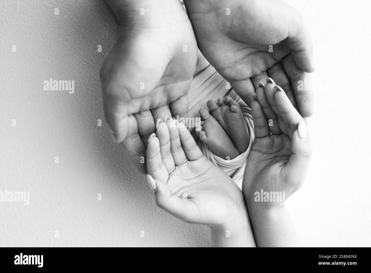 The palms of the father, the mother are holding the foot of the newborn ...