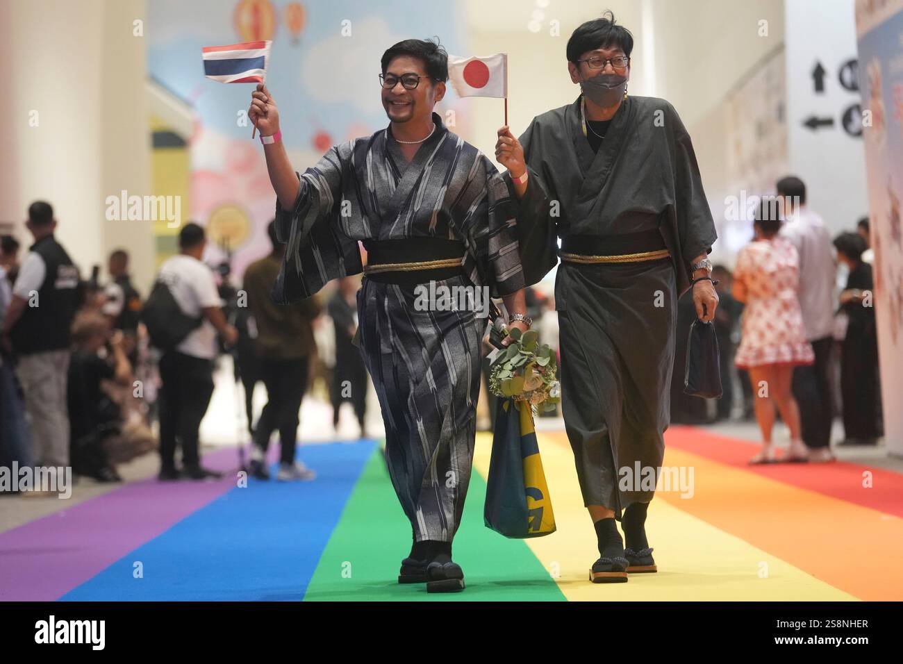 A just-married couple from the LGBTQ+ community walks on rainbow carpet ...