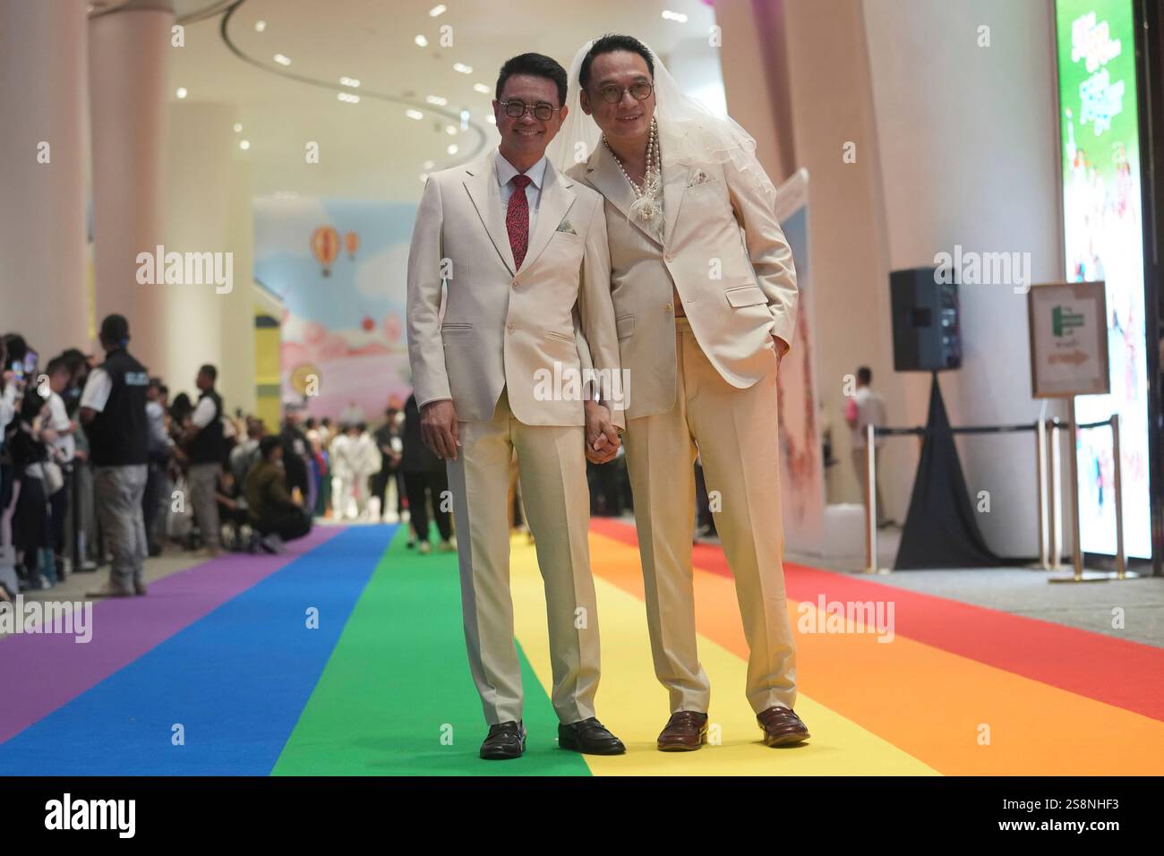 A just-married couple from the LGBTQ+ community walks on rainbow carpet ...