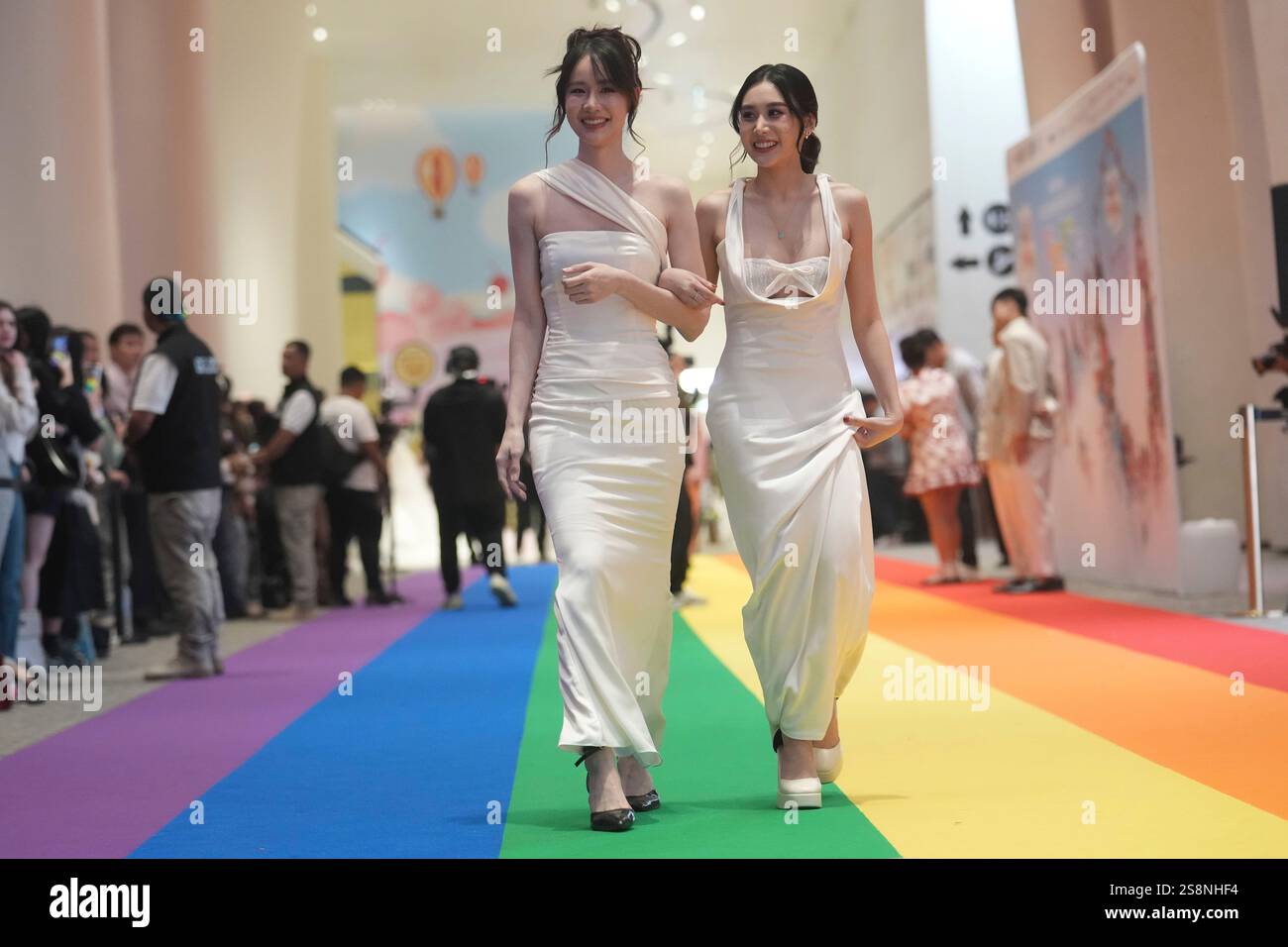 A just-married couple from the LGBTQ+ community walks on rainbow carpet ...