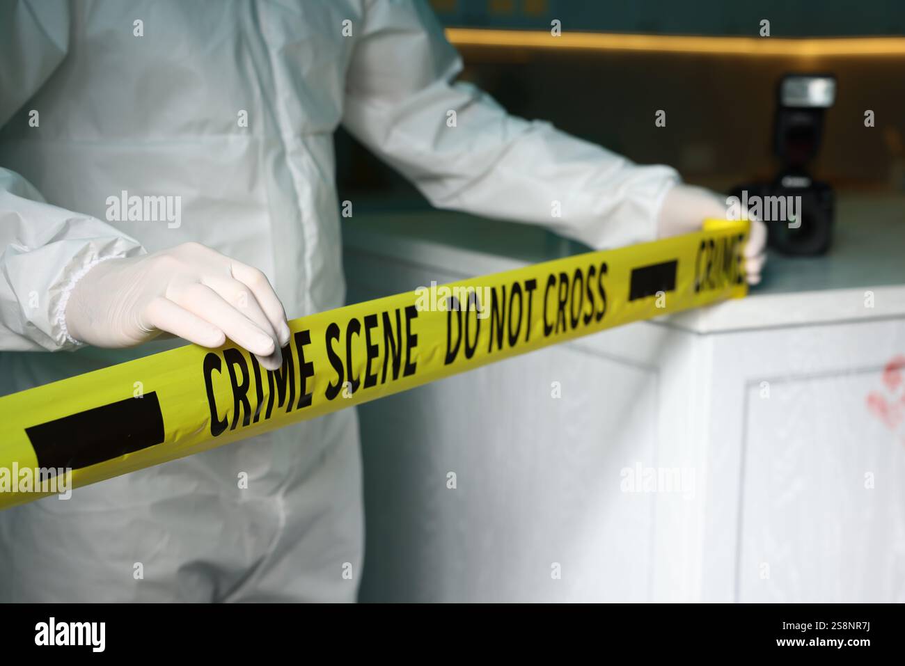 Forensic expert blocking way to crime scene with yellow tape indoors ...