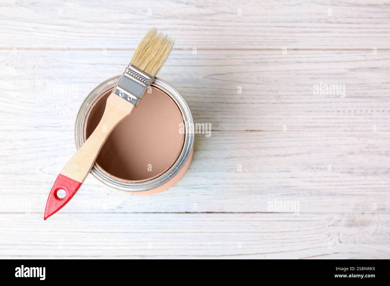Mocha mousse shade paint in can and brush on white wooden background ...