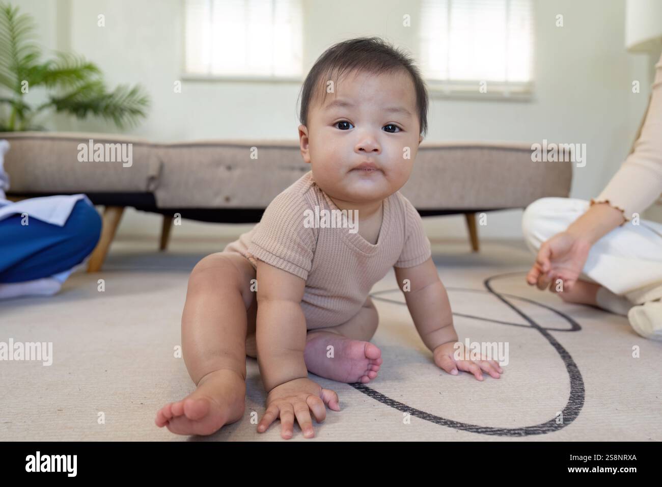 Curious baby sitting on the floor engaging with mother while ...