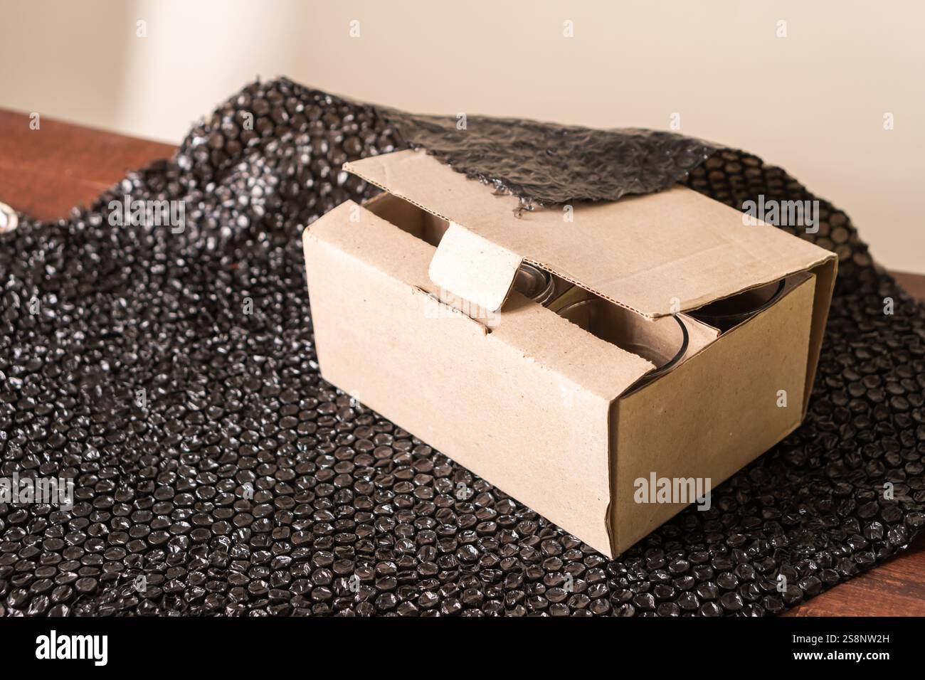 A cardboard box partially opened, resting on a textured black surface ...