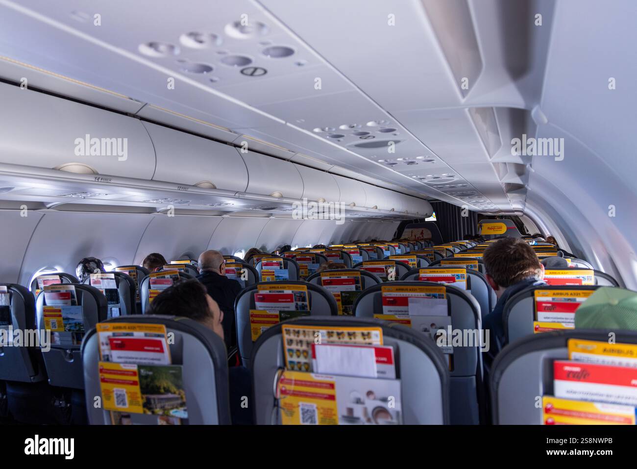 Interior view of a commercial airplane cabin with passengers seated ...