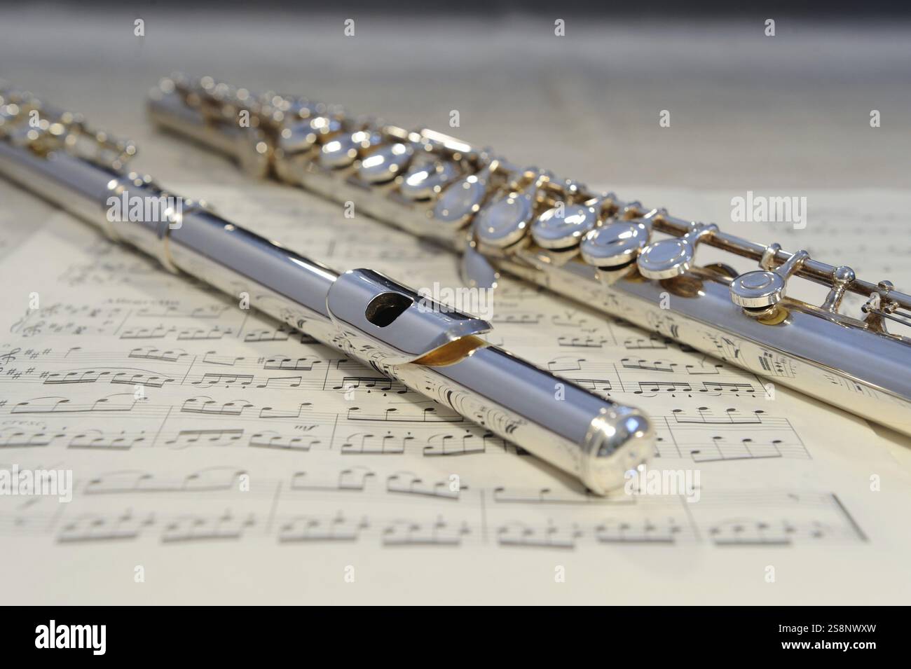 Silver flute lying on a sheet of music Stock Photo - Alamy