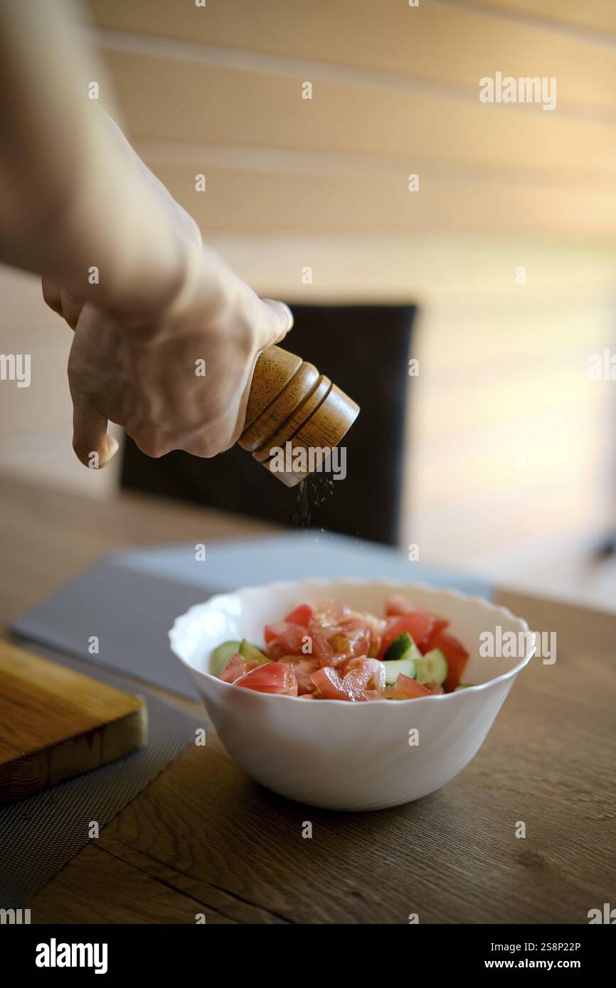 Close-up view of adding pepper from a hand mill to a bowl with ...