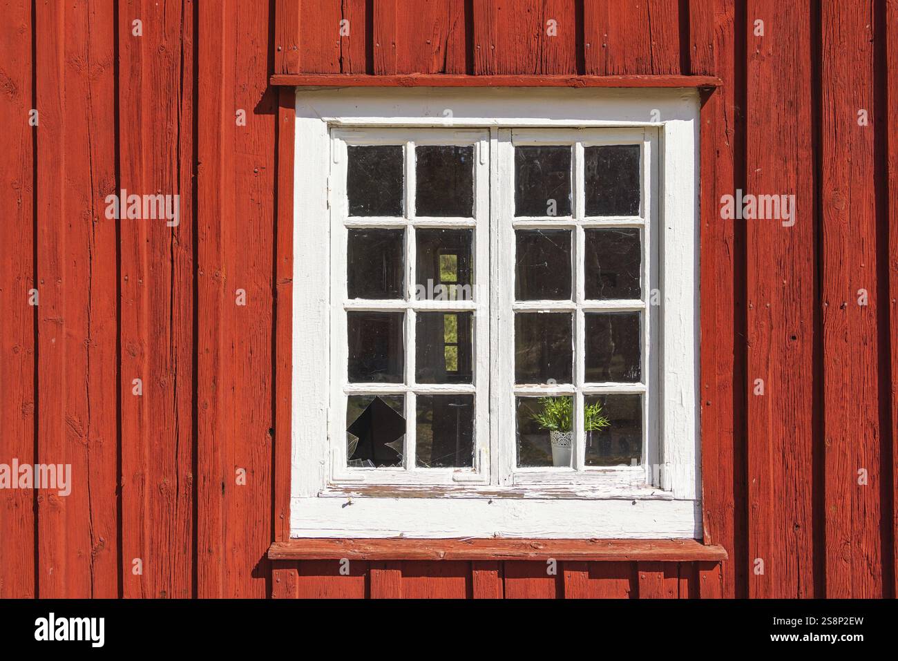 Window of an old red wooden cottage with a broken window and potted ...