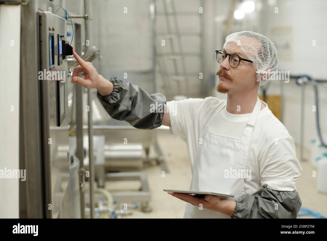 Worker wearing sterile attire operating machinery in production ...