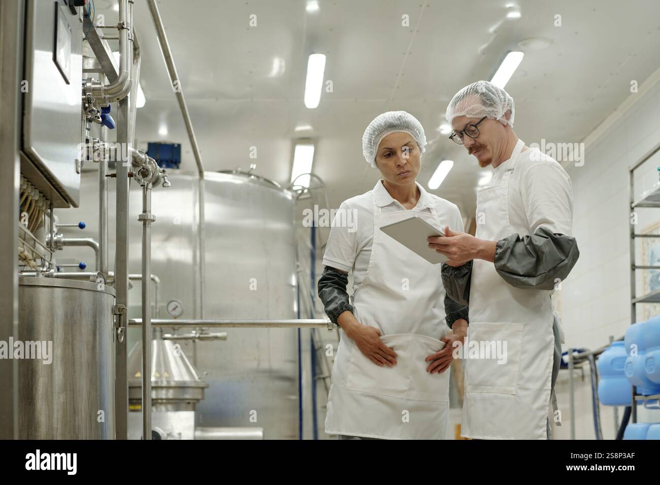 Kitchen staff in white uniforms and hairnets reviewing information on ...