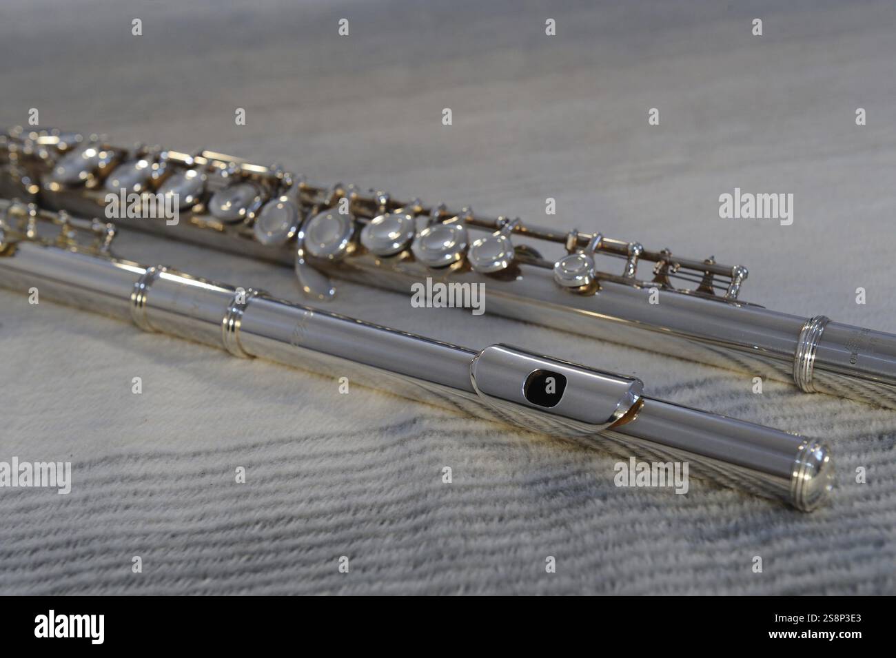 Silver transverse flute with keys on a beige background Stock Photo - Alamy