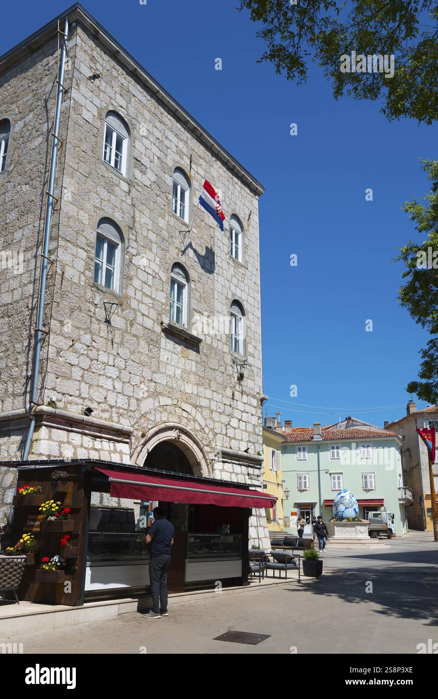 Tall stone building with characteristic windows and a flag, surrounded ...