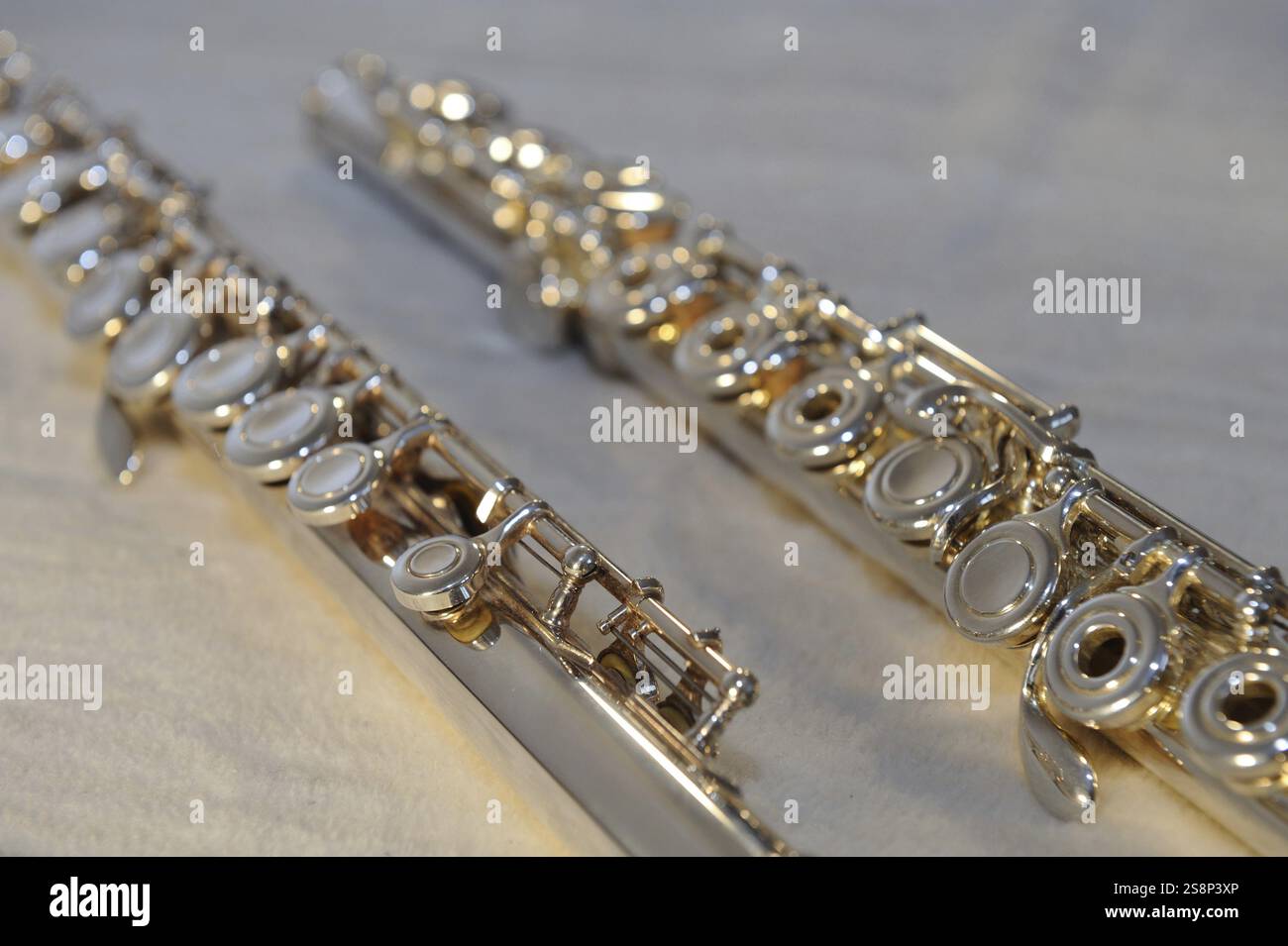 Close-up of two silver transverse flutes on a light-coloured surface ...