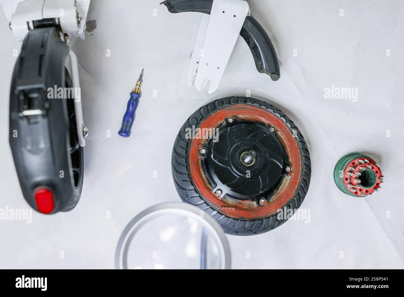 Disassembled scooter parts and repair tools laid out, including a wheel ...