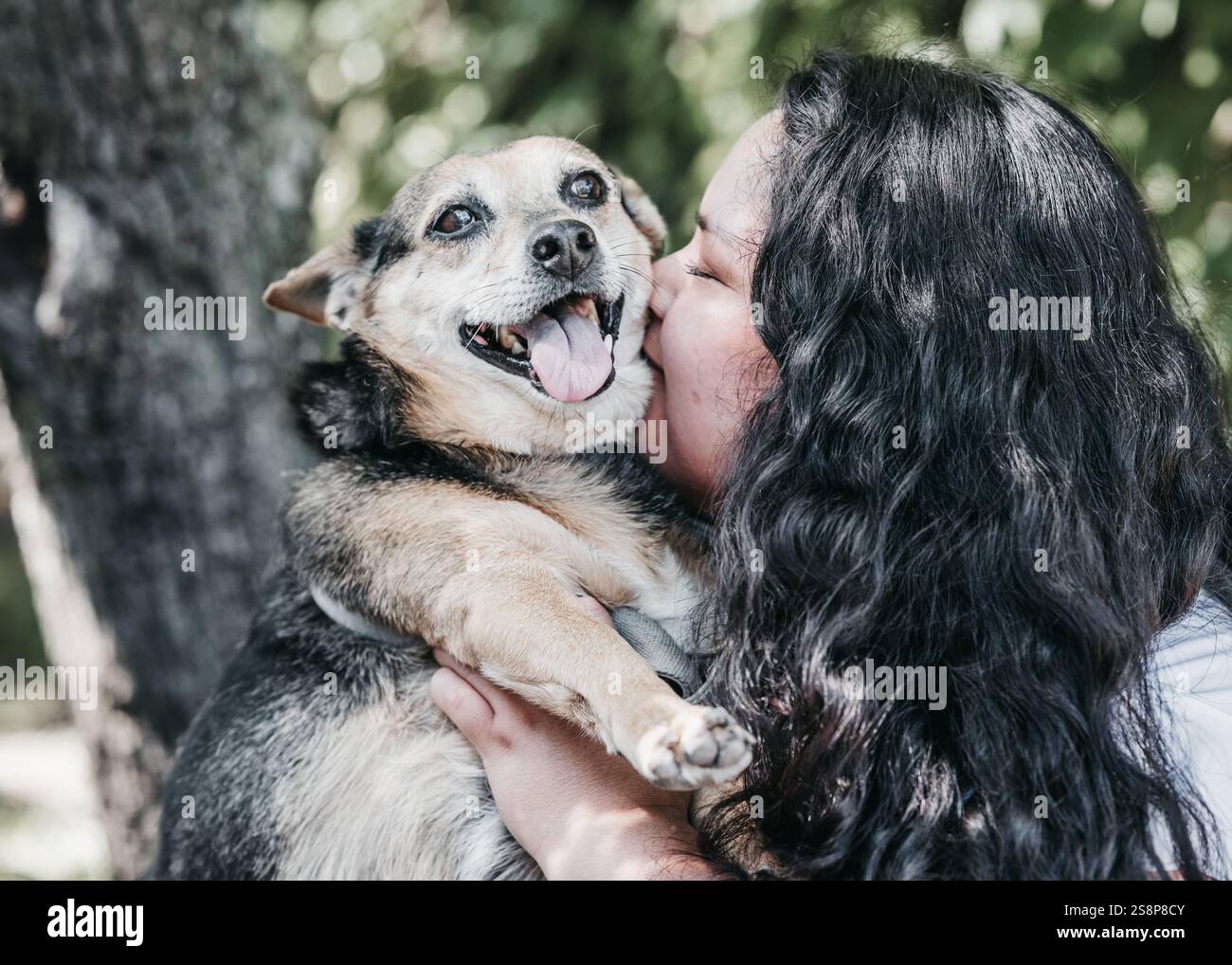Close up of a latin girl kissing her dog, they are very happy, the ...